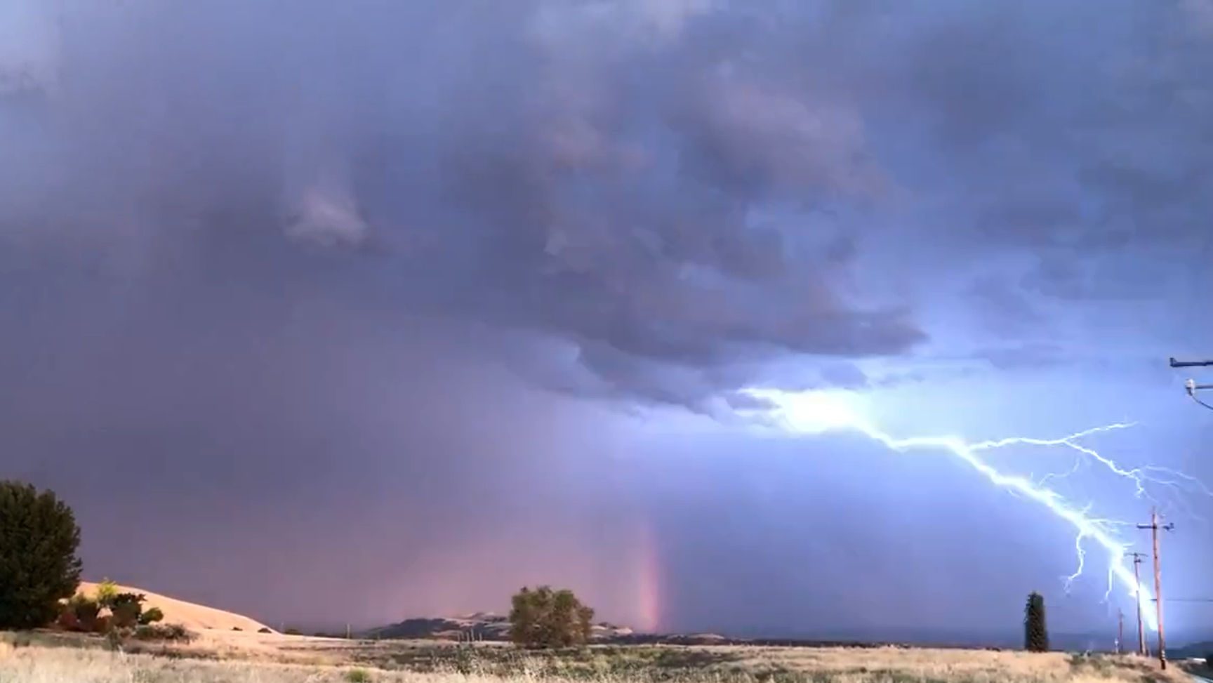 Un arcobaleno e una tempesta di fulmini illuminano il cielo in ...